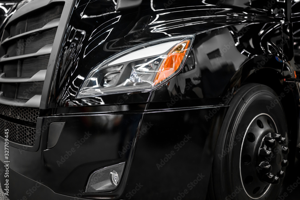 Front part of stylish black big rig semi truck tractor with light ...