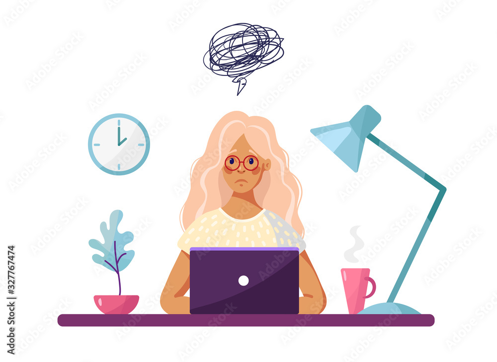 A young girl sits at a table with a laptop and feels sad or depressed ...