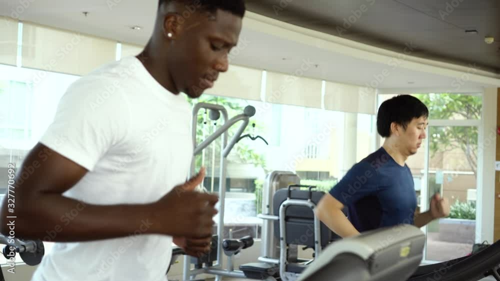 Multiracial sportsmen working out on treadmills in gym on daytime ...