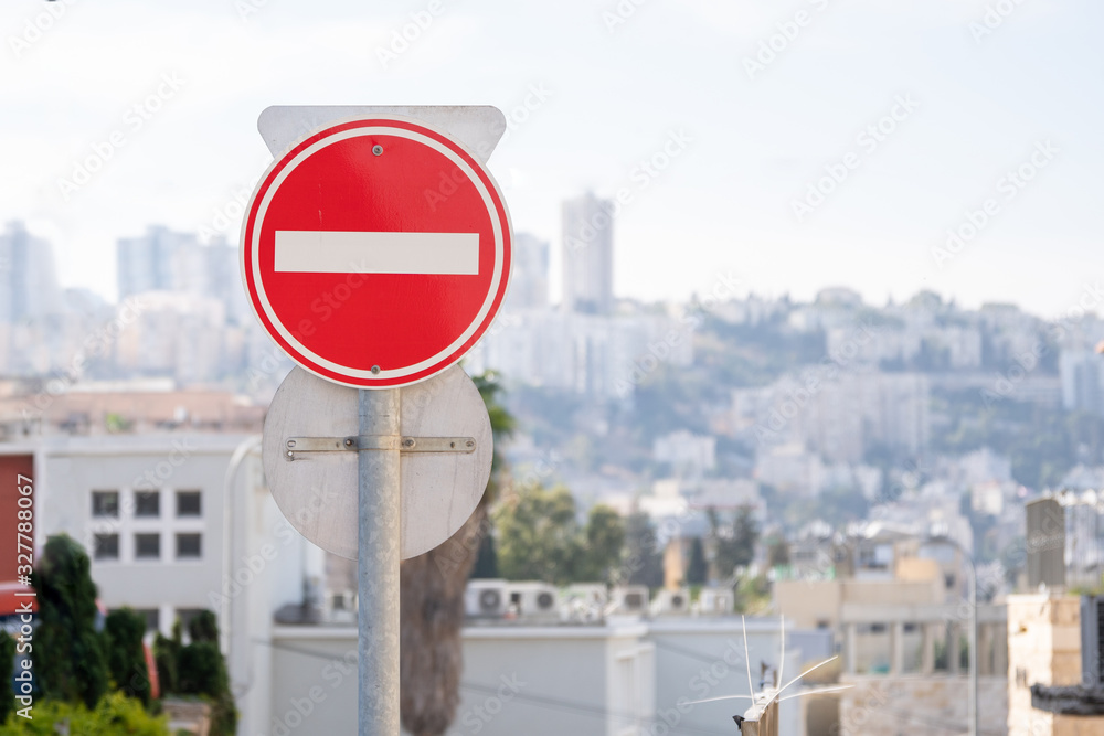 Red do not enter road sign with an Israeli town Haifa on the background ...