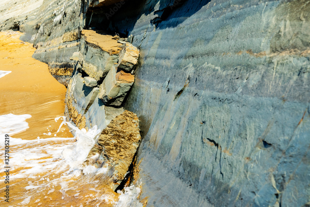 Sunny beach with beautiful clay cliff wall. Unique texture and rich ...
