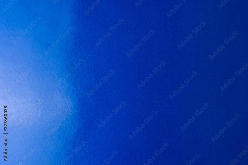 Blue background of real, shiny colored paper, illuminated by a soft ...