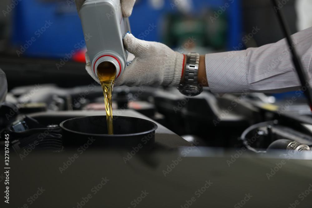 Close-up of mechanic replacing and pouring motor oil to car engine ...