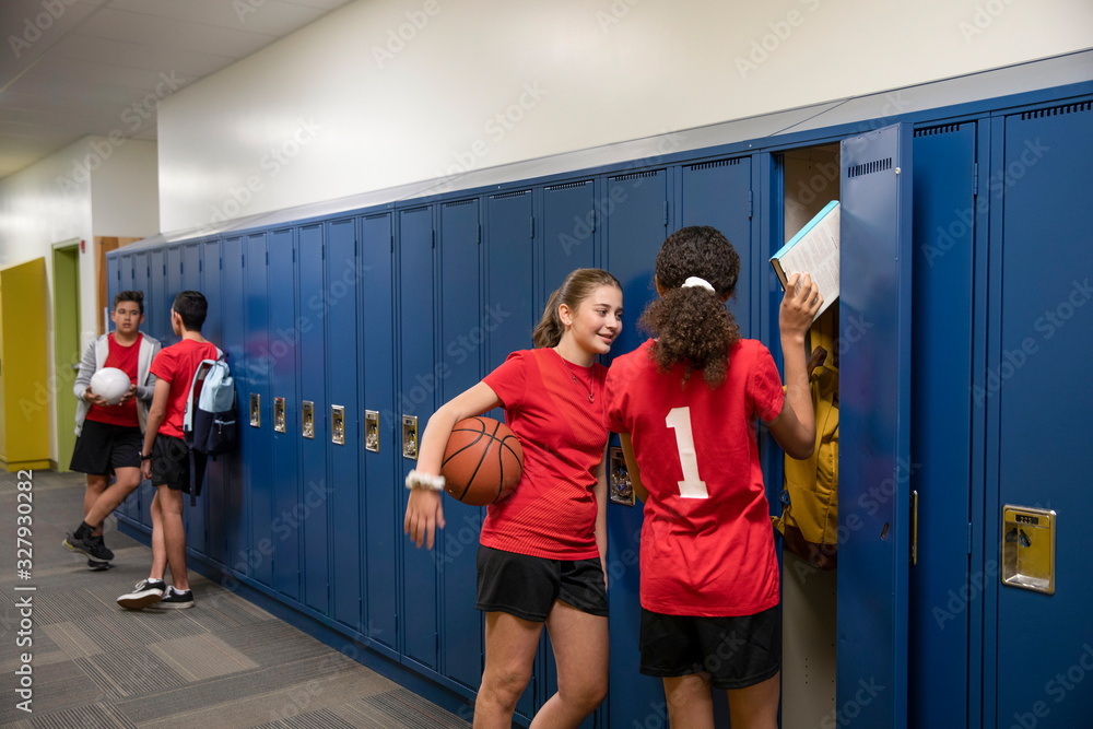 Junior high girl students in basketball uniforms at lockers in corrido ...
