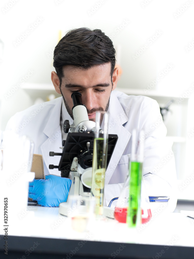 Male scientist looks inside microscope at laboratory research centre ...