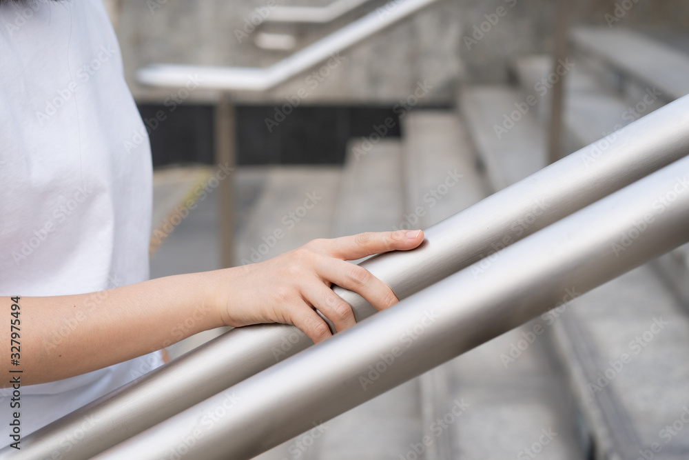 Woman walking on the stair way and grabbing on safety stair rail. Close ...