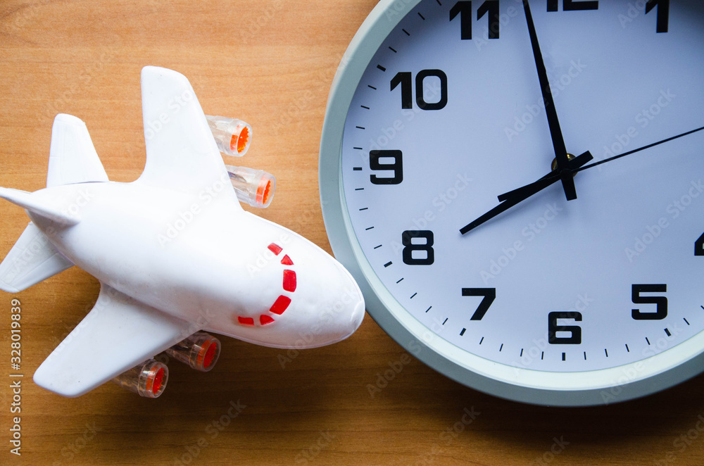 Analog clock and passenger plane. A toy airplane next to an analog ...