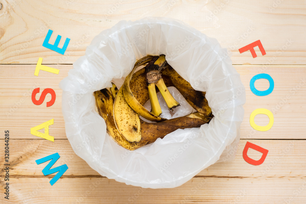 Stop wasting food. Rotten banana peel in the bin and the inscription ...