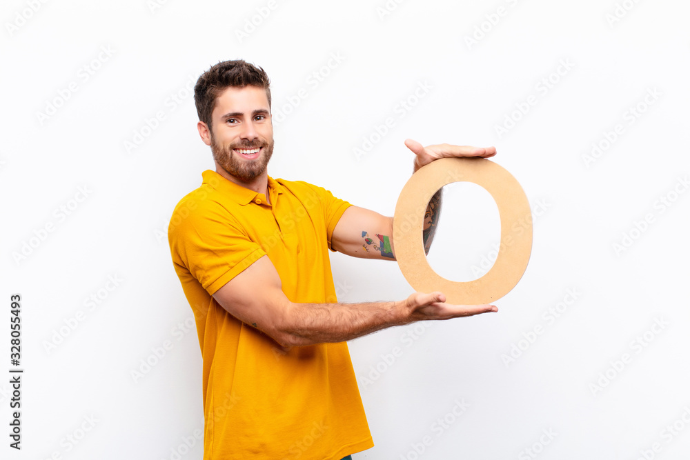 young handsome man excited, happy, joyful, holding the letter O of the ...
