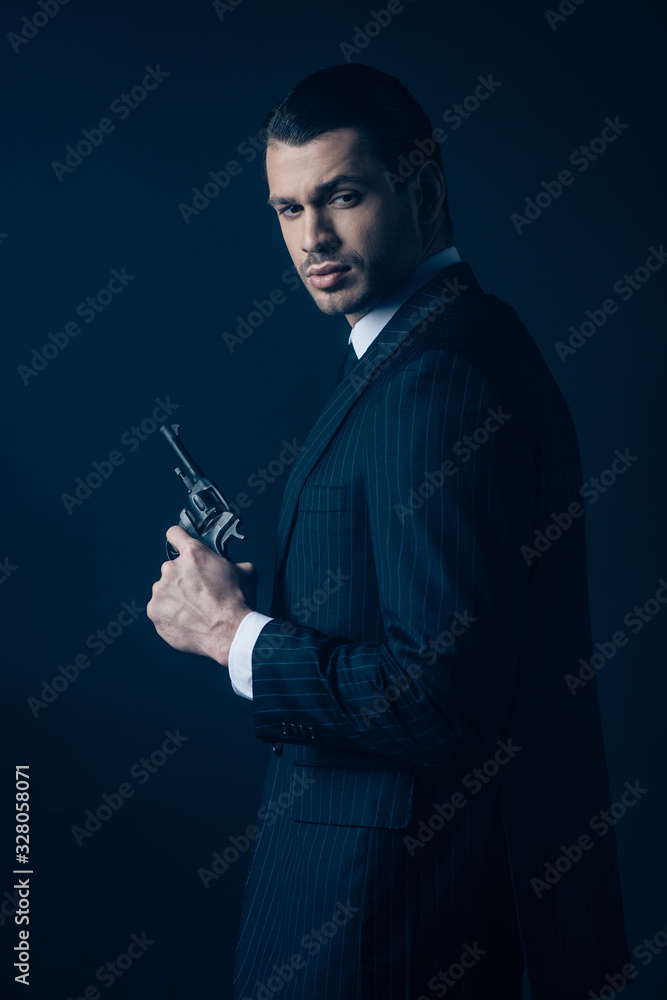 Side view of gangster with gun on dark background Stock Photo | Adobe Stock