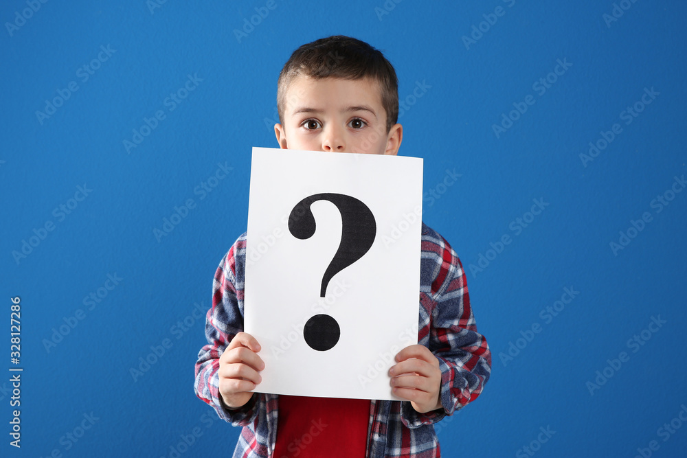Emotional little boy holding paper with question mark on blue ...