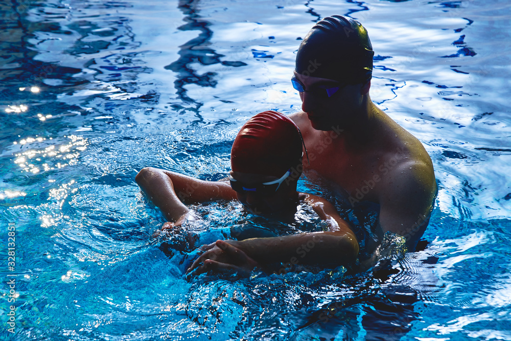 Dad and trainer teaches boy son to swim, have fun, play and splash in a ...