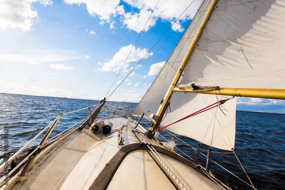 Sloop rigged yacht sailing on a clear day. A view from the deck to the ...
