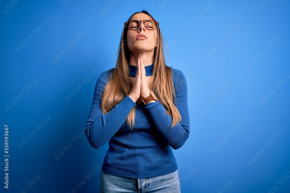 Young beautiful blonde woman with blue eyes wearing glasses standing ...