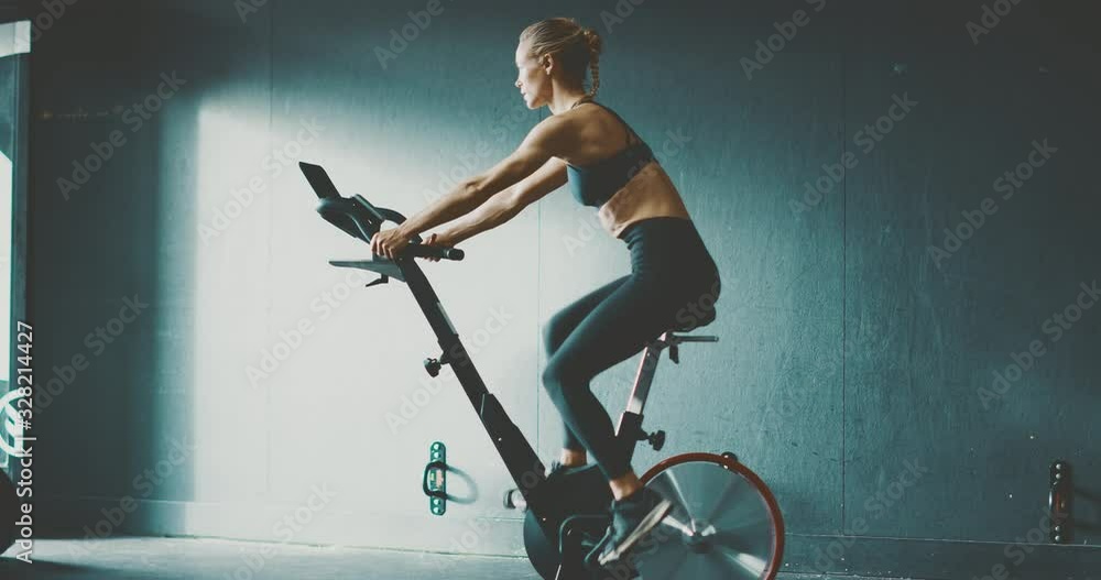 Fit attractive woman working out on a stationary bike in the gym ...