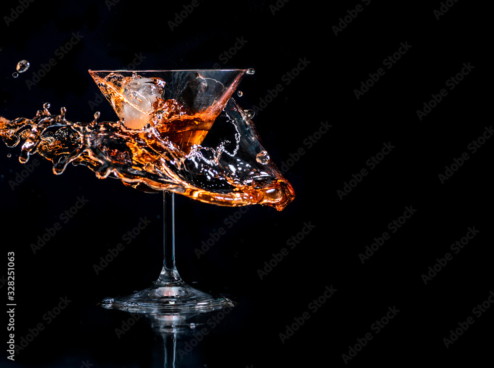 Cocktail splash in martini glass over black background with copyspace ...