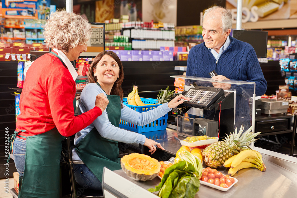 Employee helps young woman as a cashier trainee Stock Photo | Adobe Stock