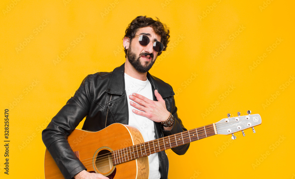 young musician man looking sad, hurt and heartbroken, holding both ...