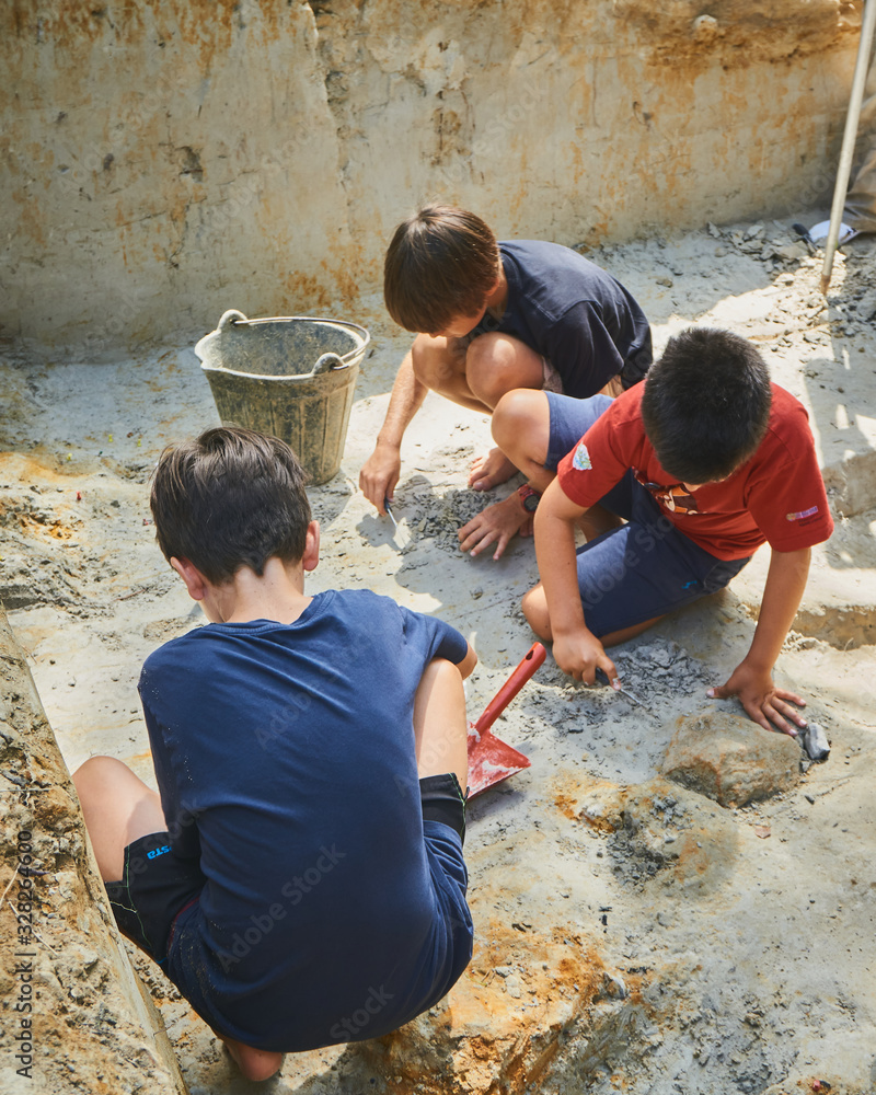 Three children kids playing and helping in archaeological excavation ...