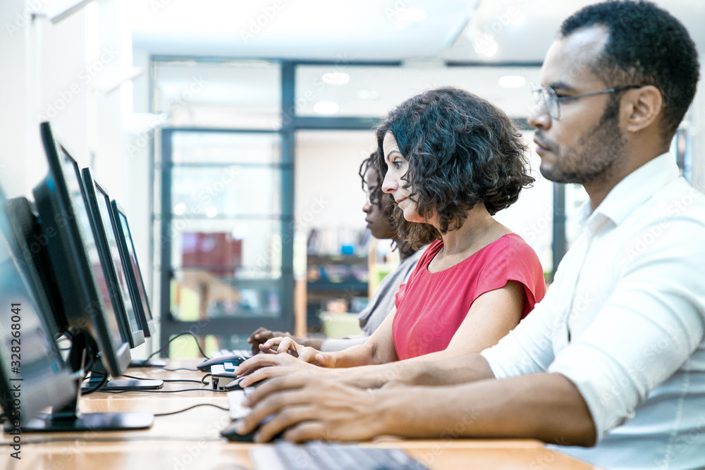 Mix raced adult students training in computer class. Row of man and ...