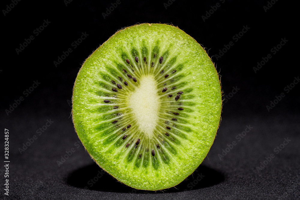 Detailed cross section of a fresh illuminated kiwi fruit cut in half ...