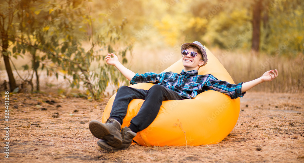 Handsome young man in hat and sunglasses lying on inflatable sofa ...