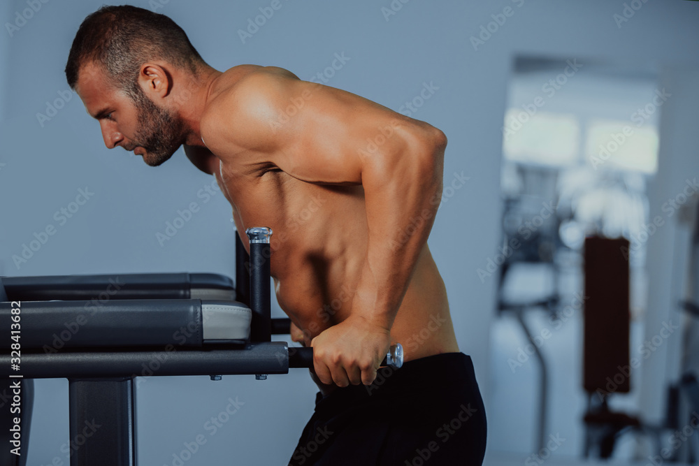 Foto de Handsome muscular man working out hard at gym. Training without ...