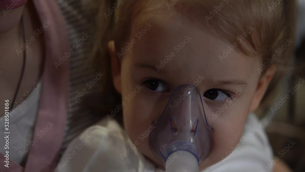 Little girl makes inhalation using a compressor inhaler while sitting ...