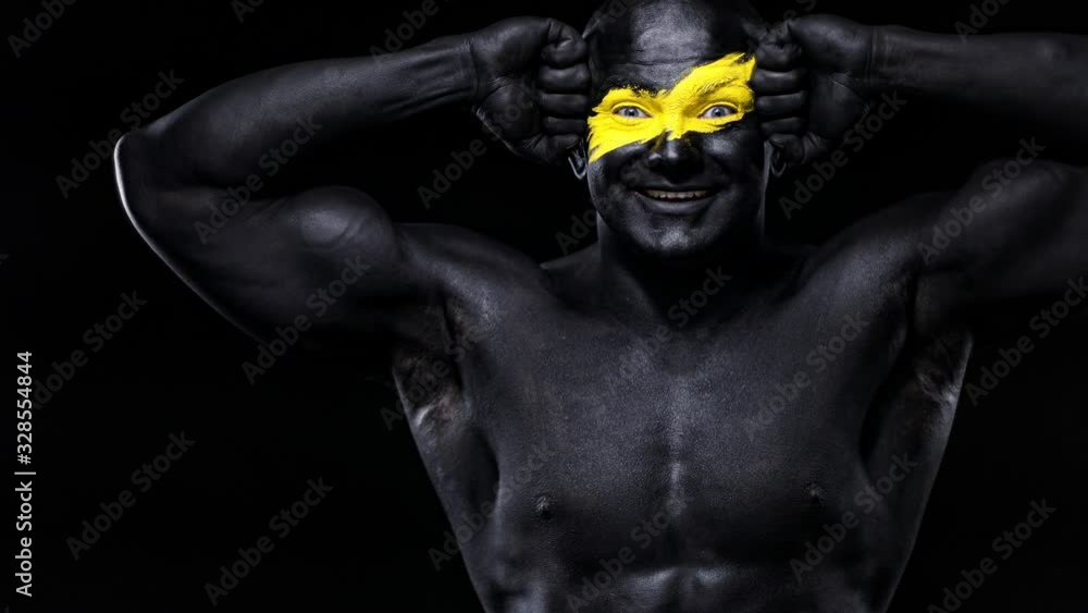 Man bodybuilder athlete with yellow color on face art and black body ...
