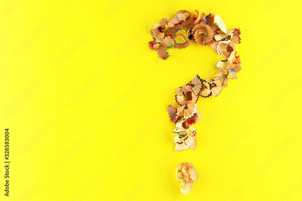 question mark made of colored pencil shavings on a yellow background ...