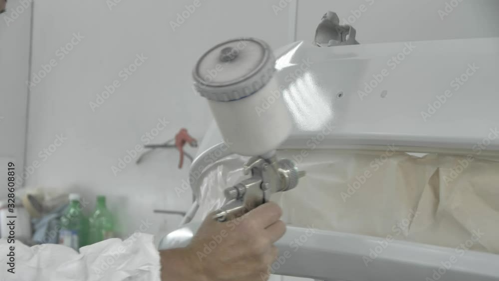 The process of painting the bumper of a white car in a spray booth. Man ...