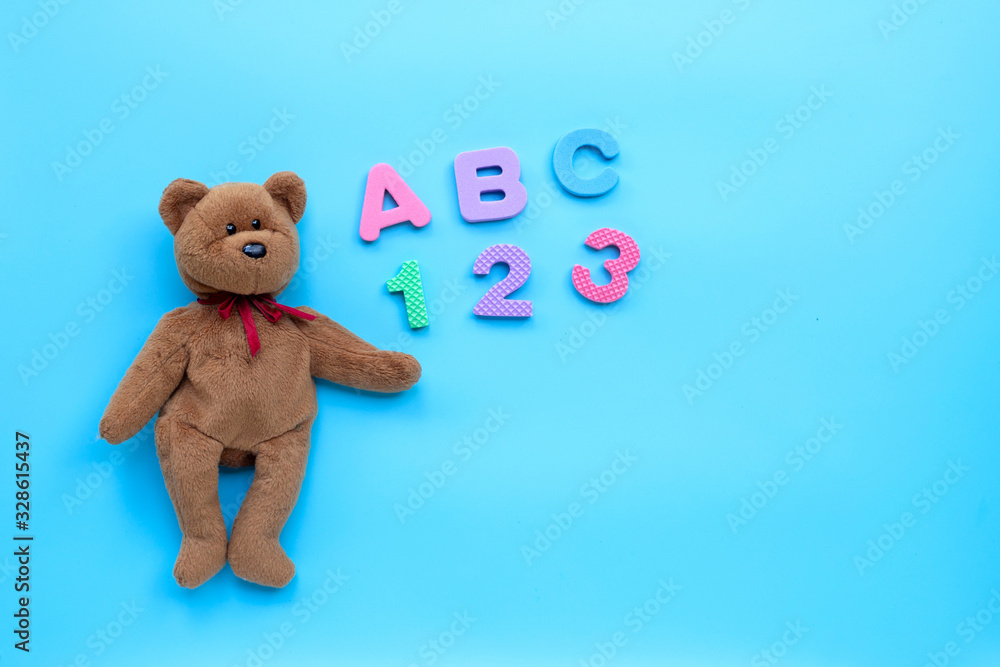 Brown bear toy with english alphabet and numerals on blue background ...