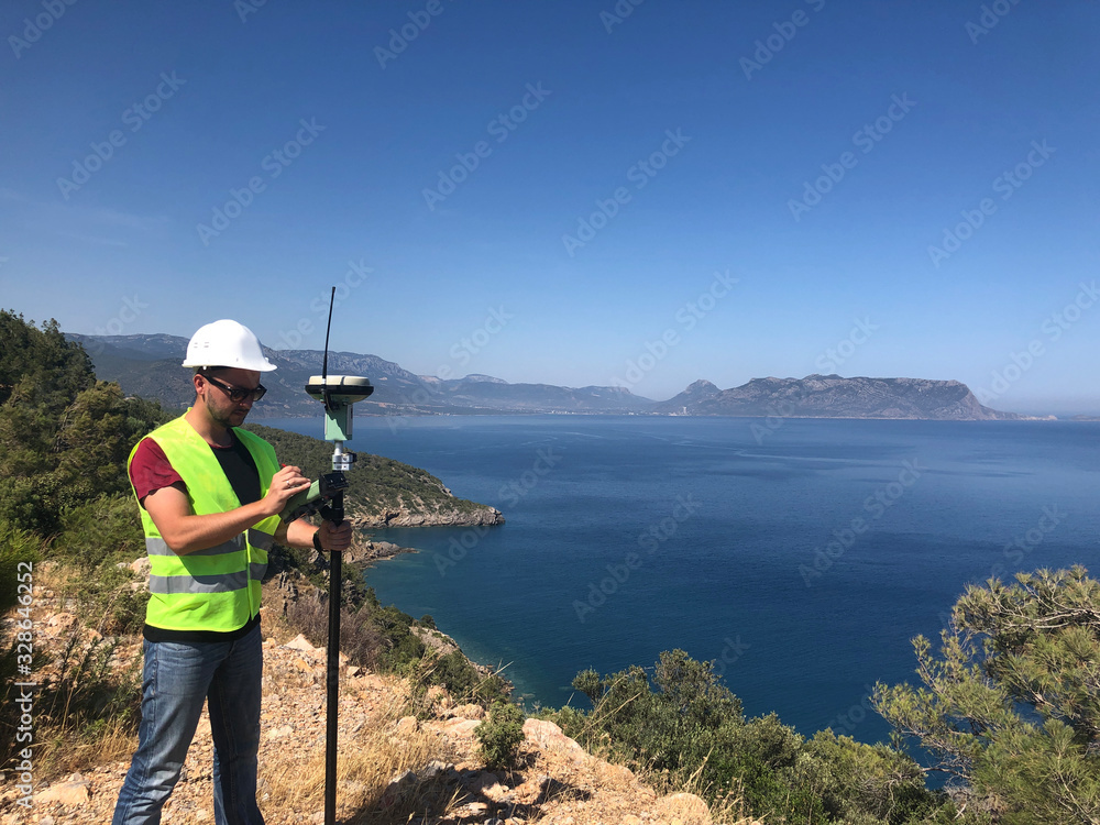 Geodetic engineer surveyor in white hard hat doing measurements with ...