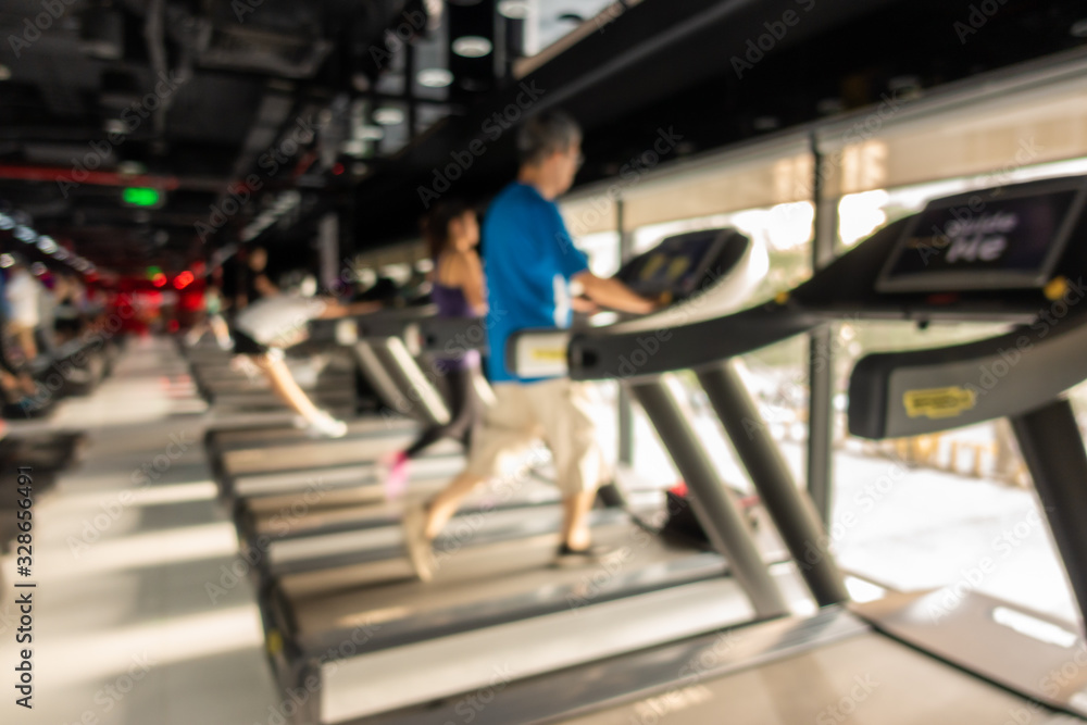 Blurred of fitness gym center interior background with two rows of ...