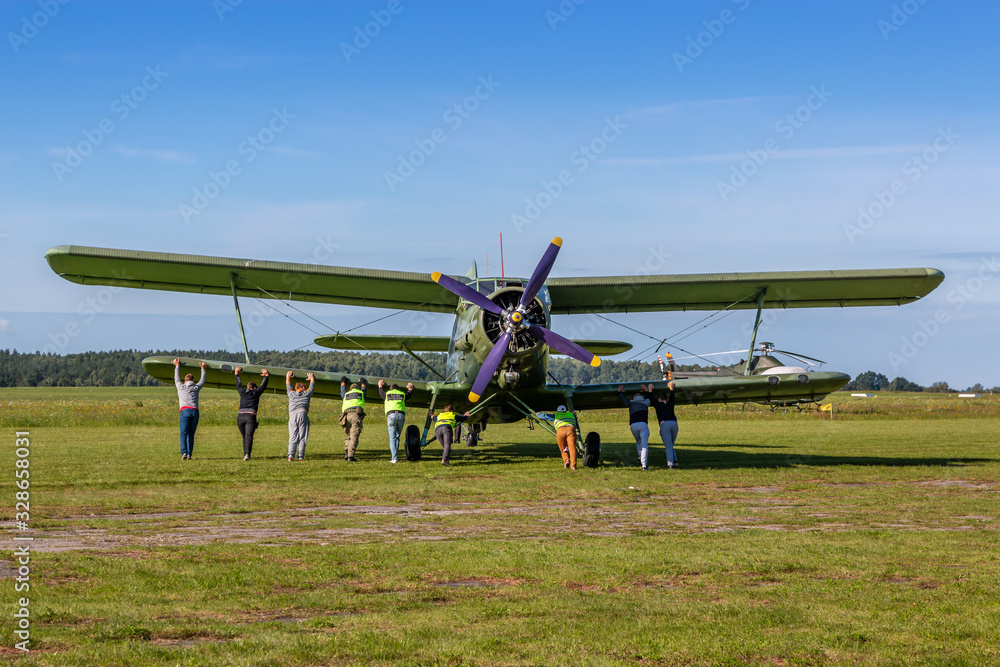 Old bi-plane being pushed back by an airfield crew Stock Photo | Adobe ...