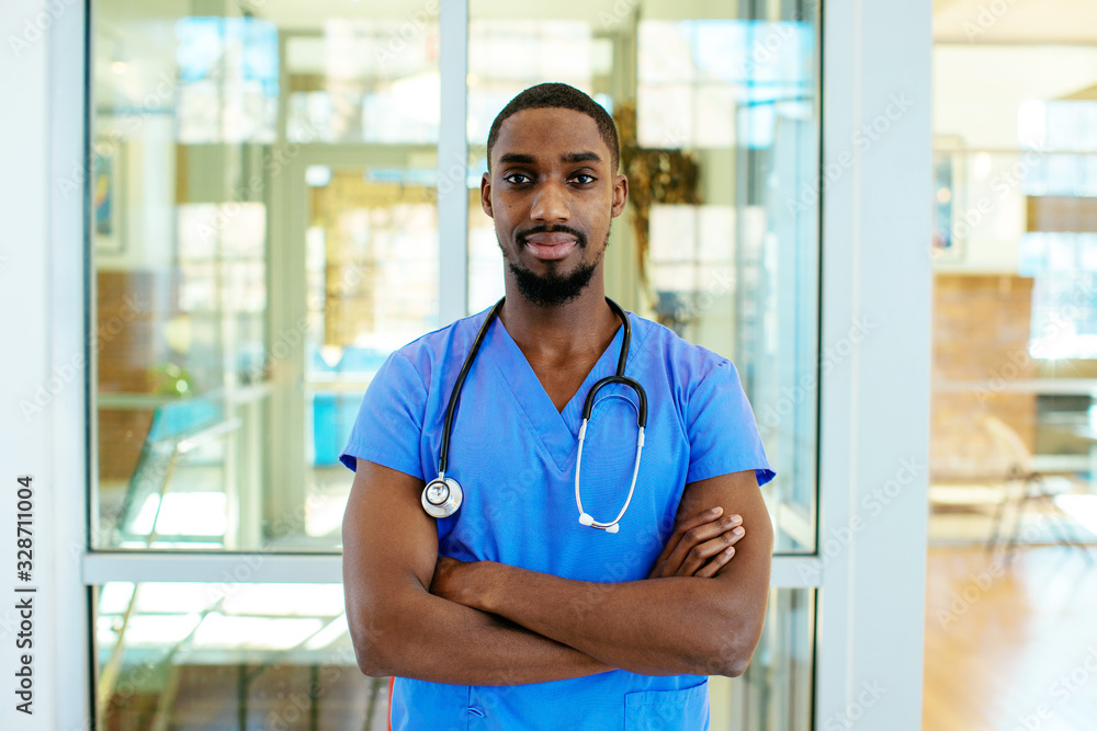 Portrait of a serious young male doctor or nurse wearing blue scrubs ...