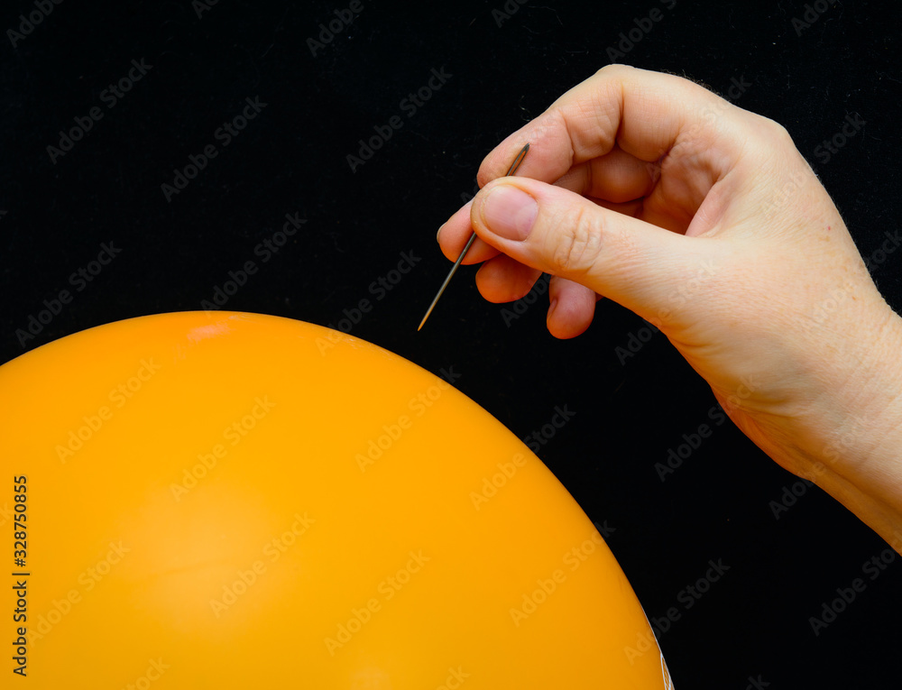 In a female hand a sewing needle. The needle is above the surface of an ...