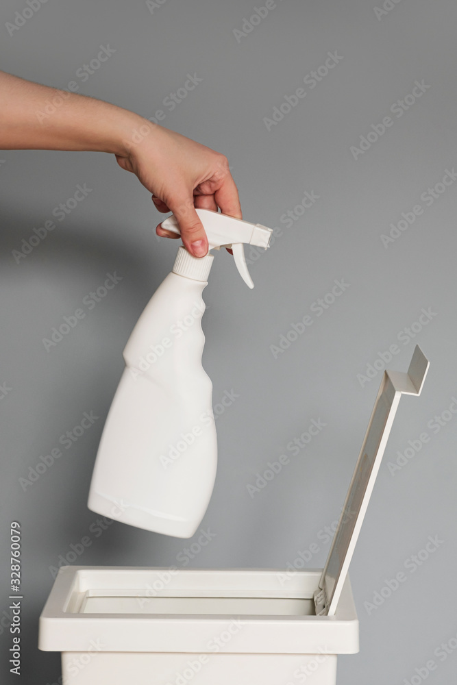 A hand puts an empty white plastic bottle of cleaning products in a ...