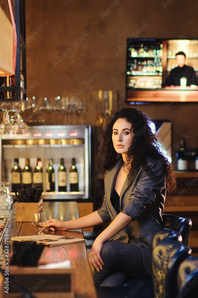 Elegant lady in a business suit, in a restaurant at a bar counter alone ...