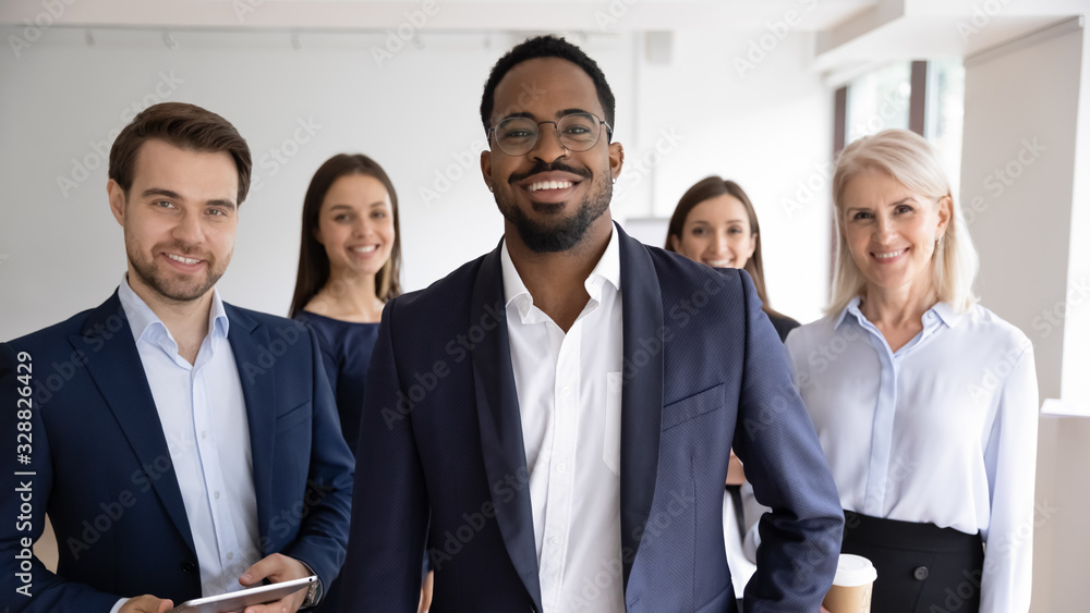 Group portrait of smiling motivated multiracial businesspeople stand ...