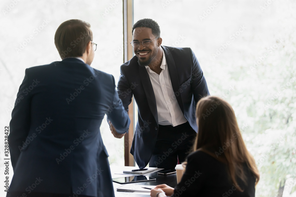 Smiling multiracial male business partners handshake greeting getting ...