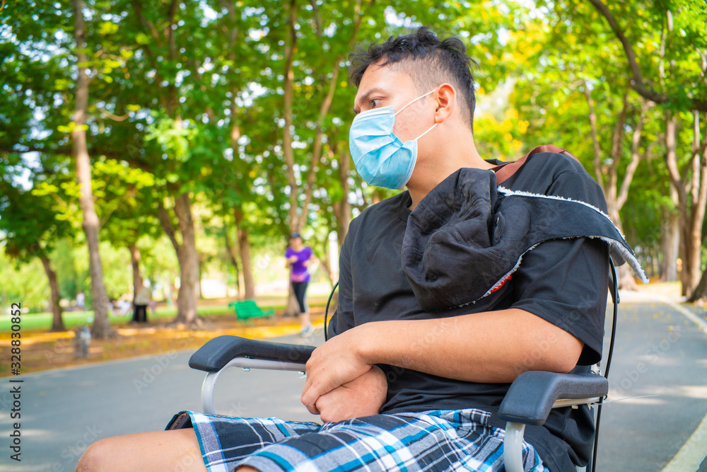 Disable man sitting on wheelchair in city green park with mask protect ...