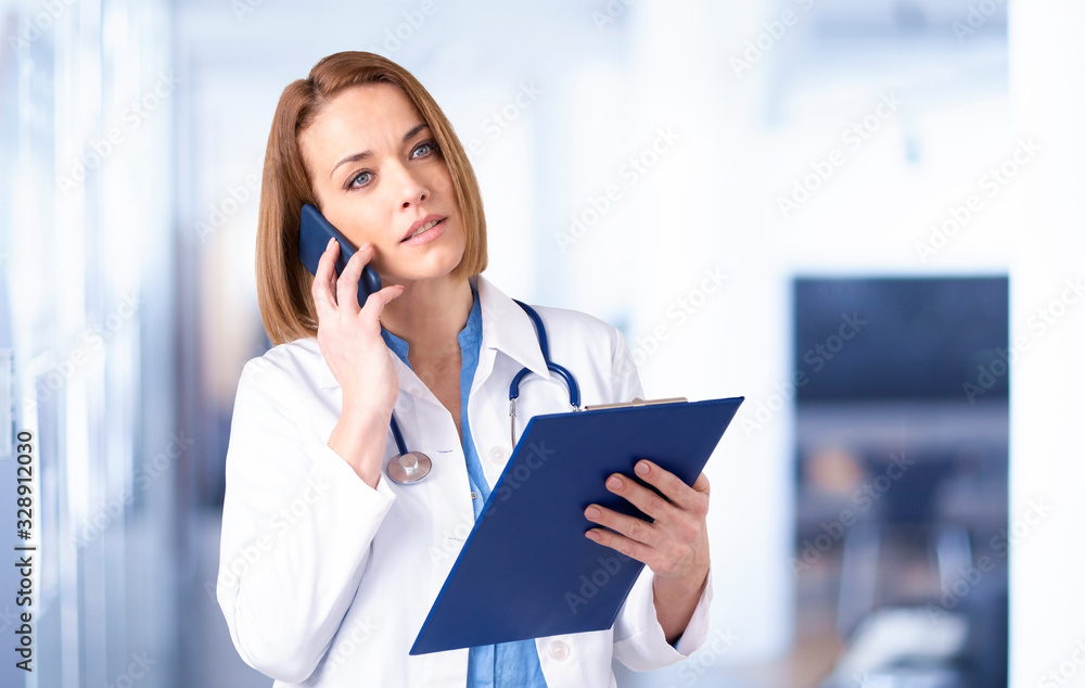 Female doctor portrait while talking with somebody on her mobile phone ...