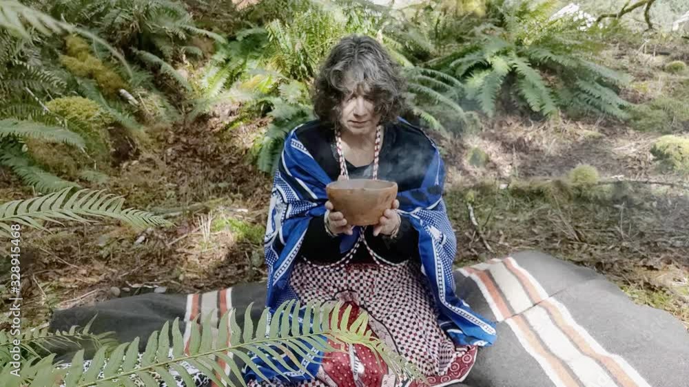 Woman shaman lifting a burning bowl and blowing the smoke praying to ...