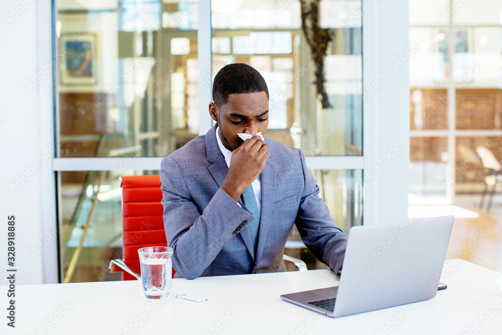 Portrait of a sick young man in business suit having a cold, blowing ...