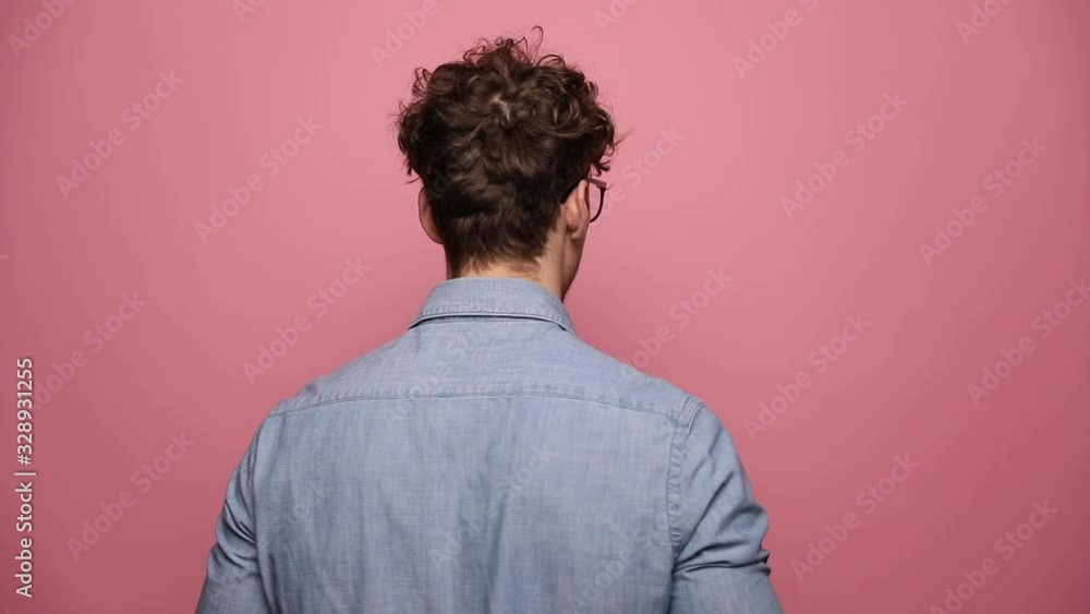 young casual man wearing glasses posing in rear view then turning in ...