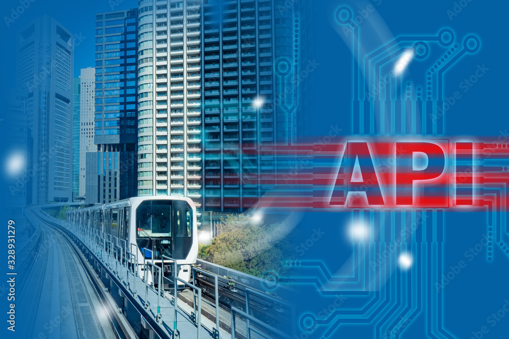 API logo next to a train. The train rides next to a skyscraper ...