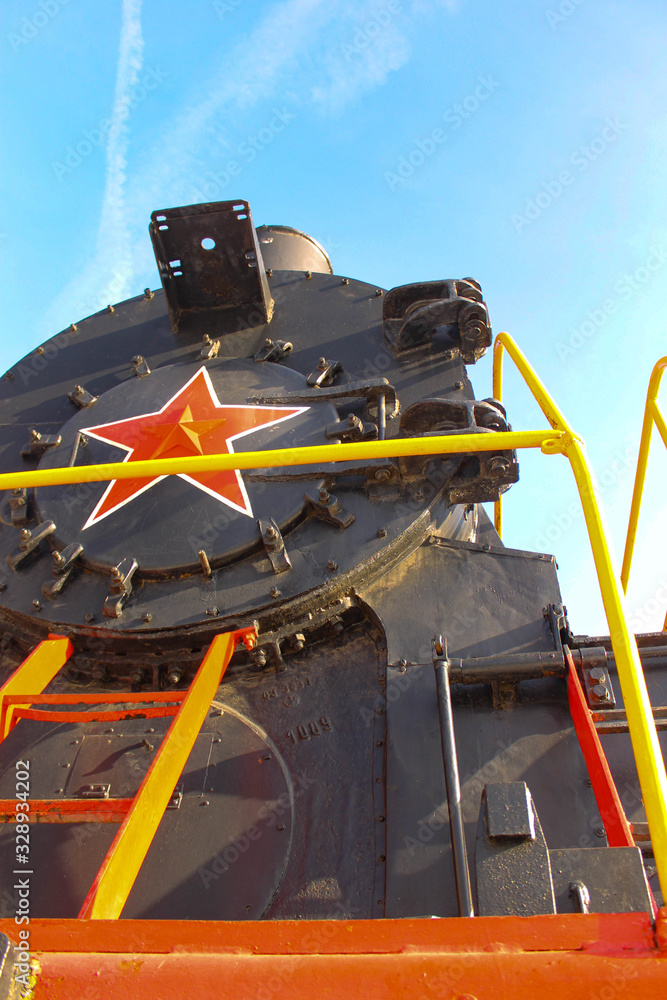 Soviet old steam train front side with a red star on the blue sky ...