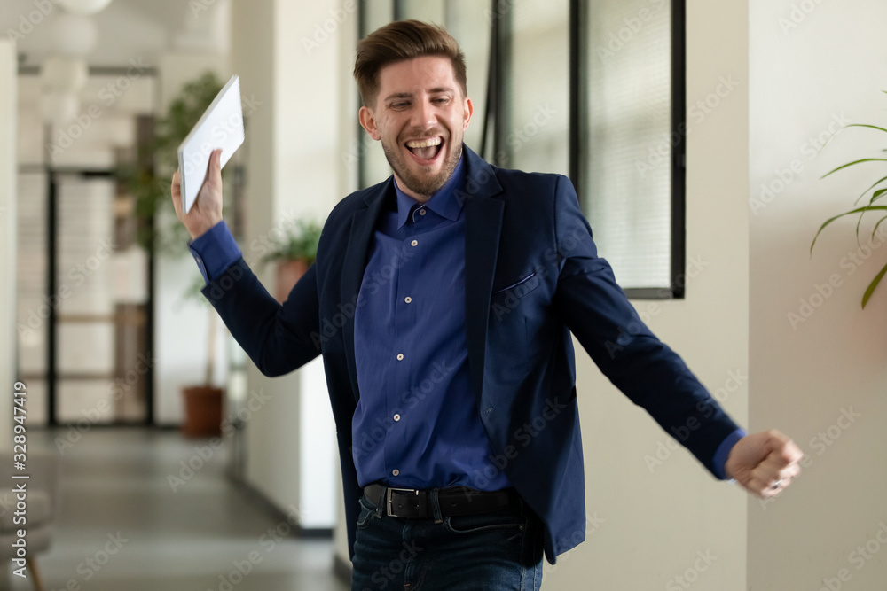 Happy millennial male employee dance in office corridor celebrate end ...