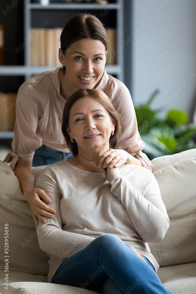 Vertical image portrait happy grownup daughter hugging pleasant older brunette mother resting on ...